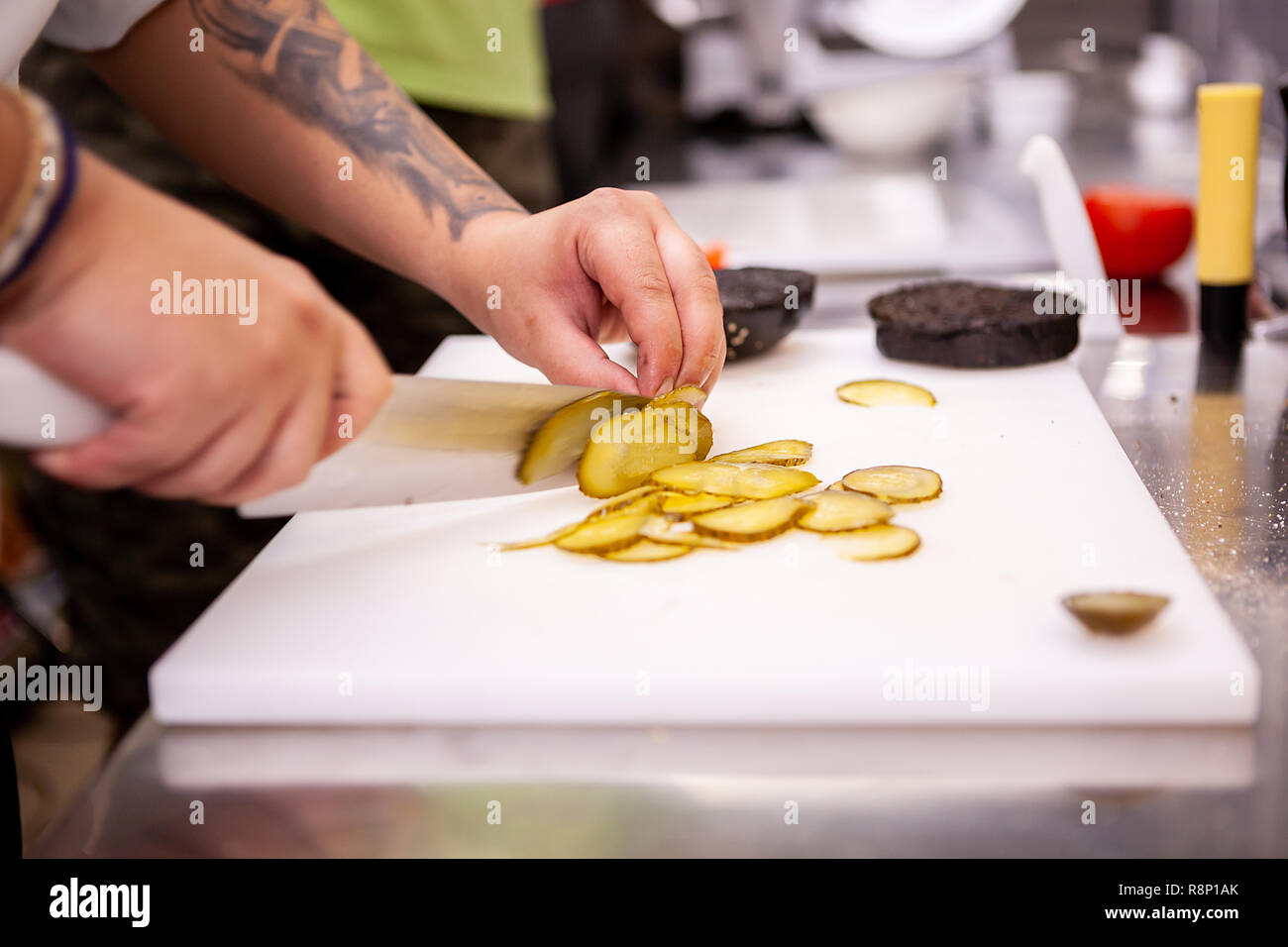 Chef slices pickles for delicious burger in restaurant. Food ...