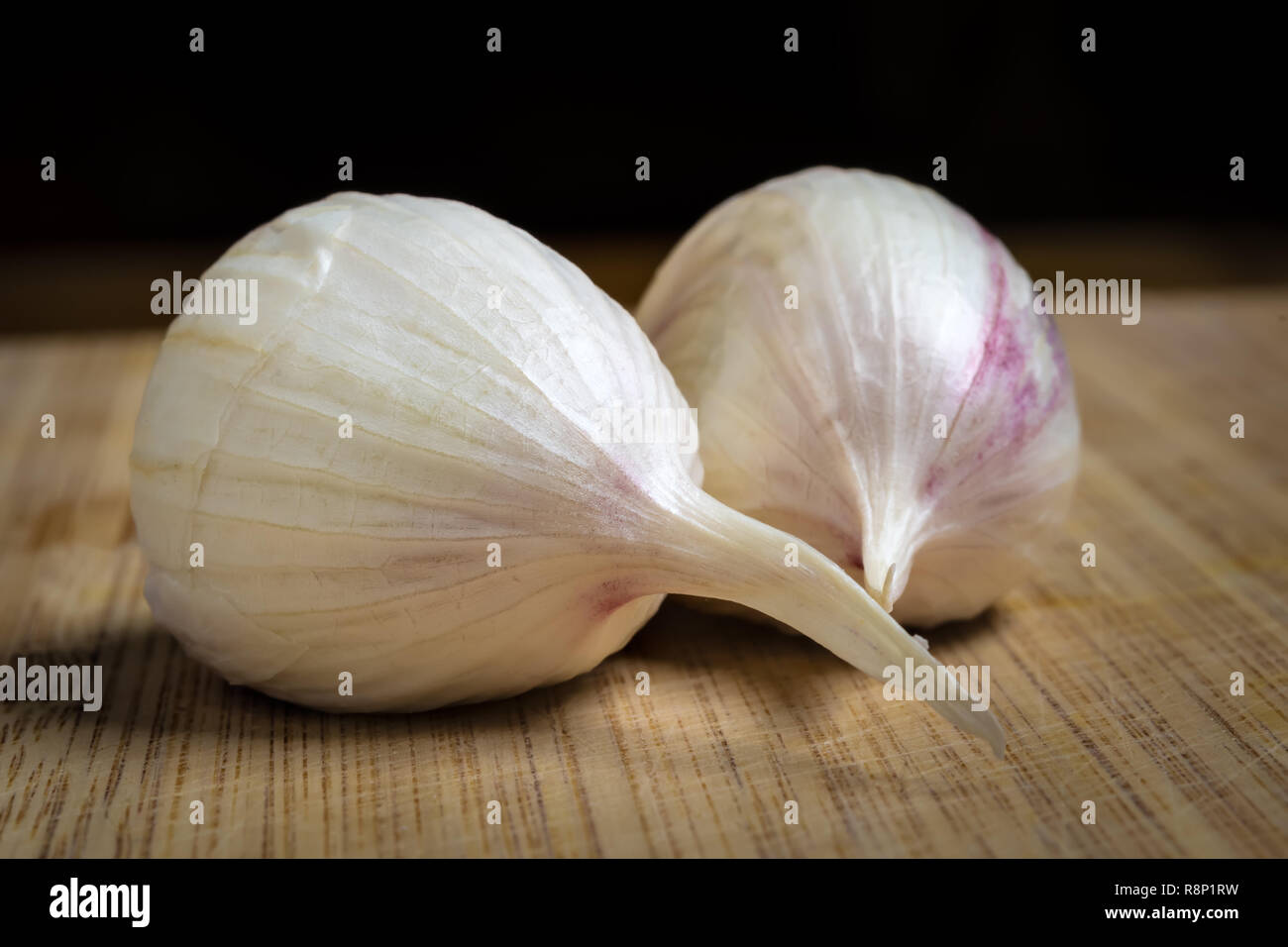 Closeup of two fresh garlic clove on a table with dark background Stock ...
