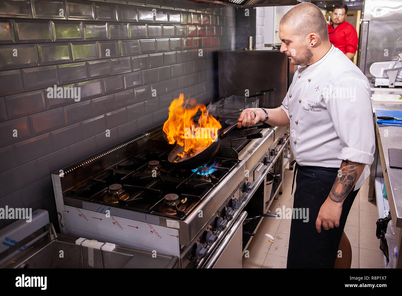 Male cook making flambe seafood at stove in restaurant kitchen.Tasty ...