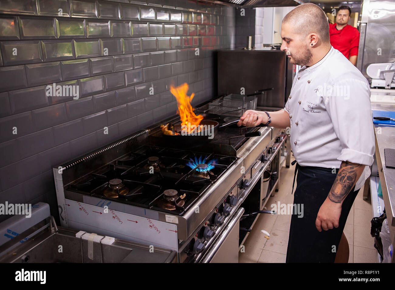 Male cook making flambe seafood at stove in restaurant kitchen.Tasty ...