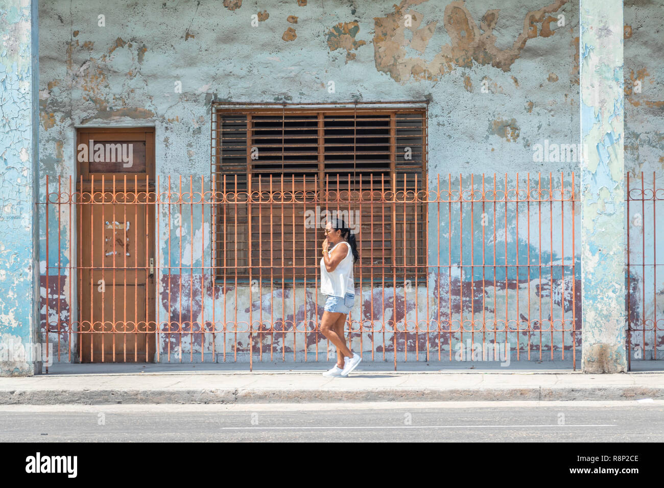 cuban woman walking down havana street in front of distressed wall in ...