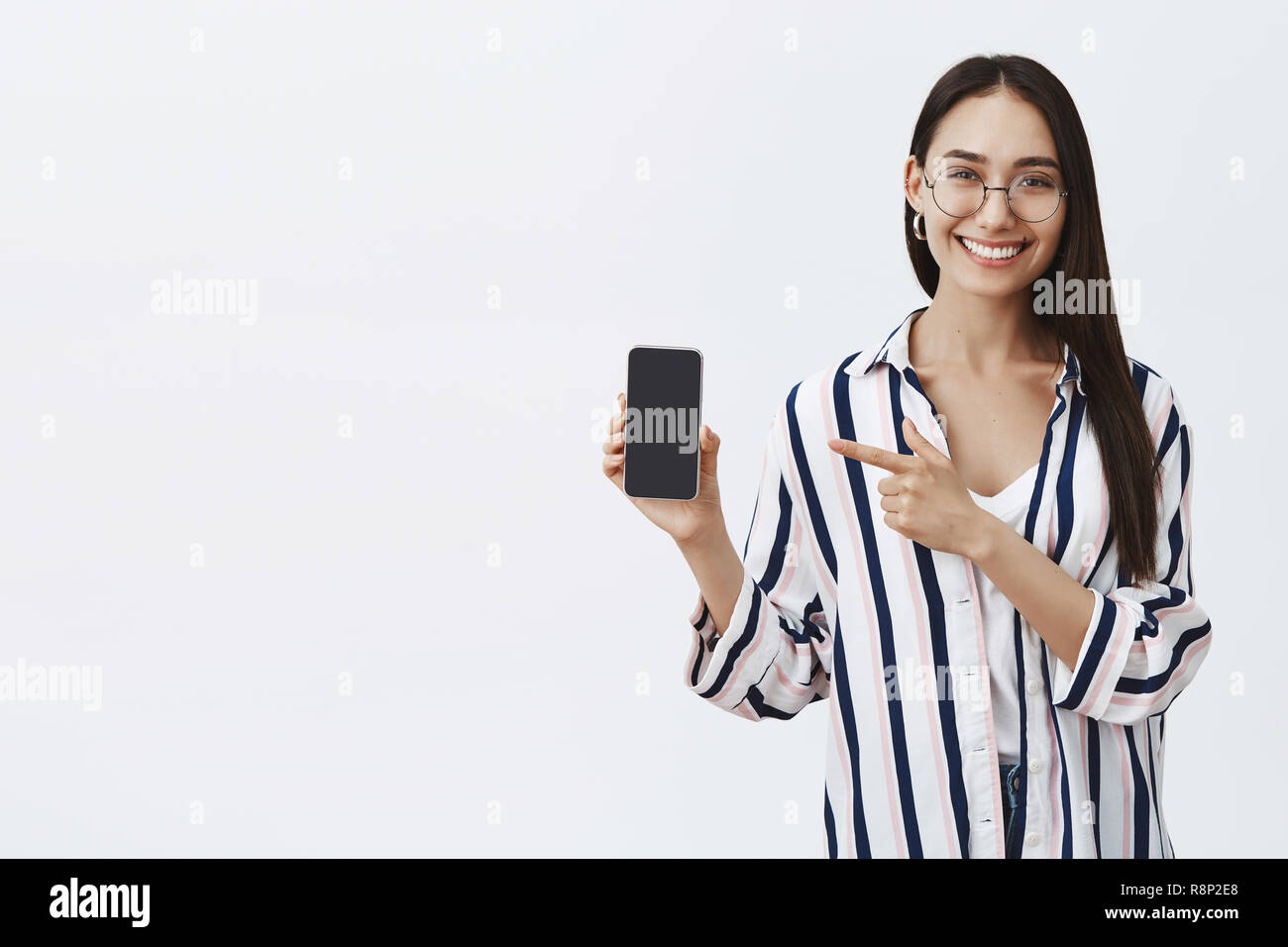 Look at this smartphone. Portrait of good-looking pleased fashionable ...