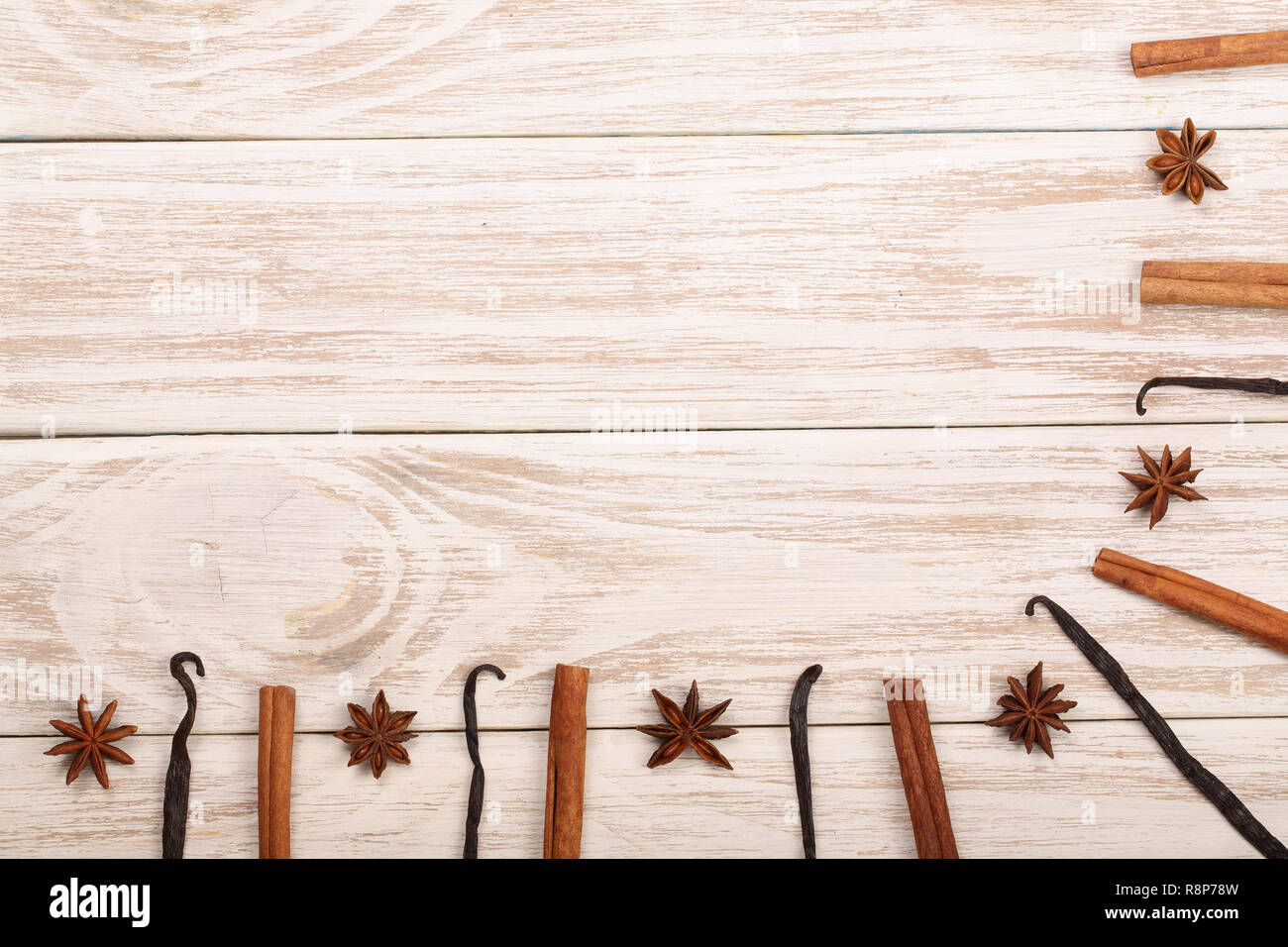 Frame of vanilla sticks, cinnamon and star anise on white wooden ...