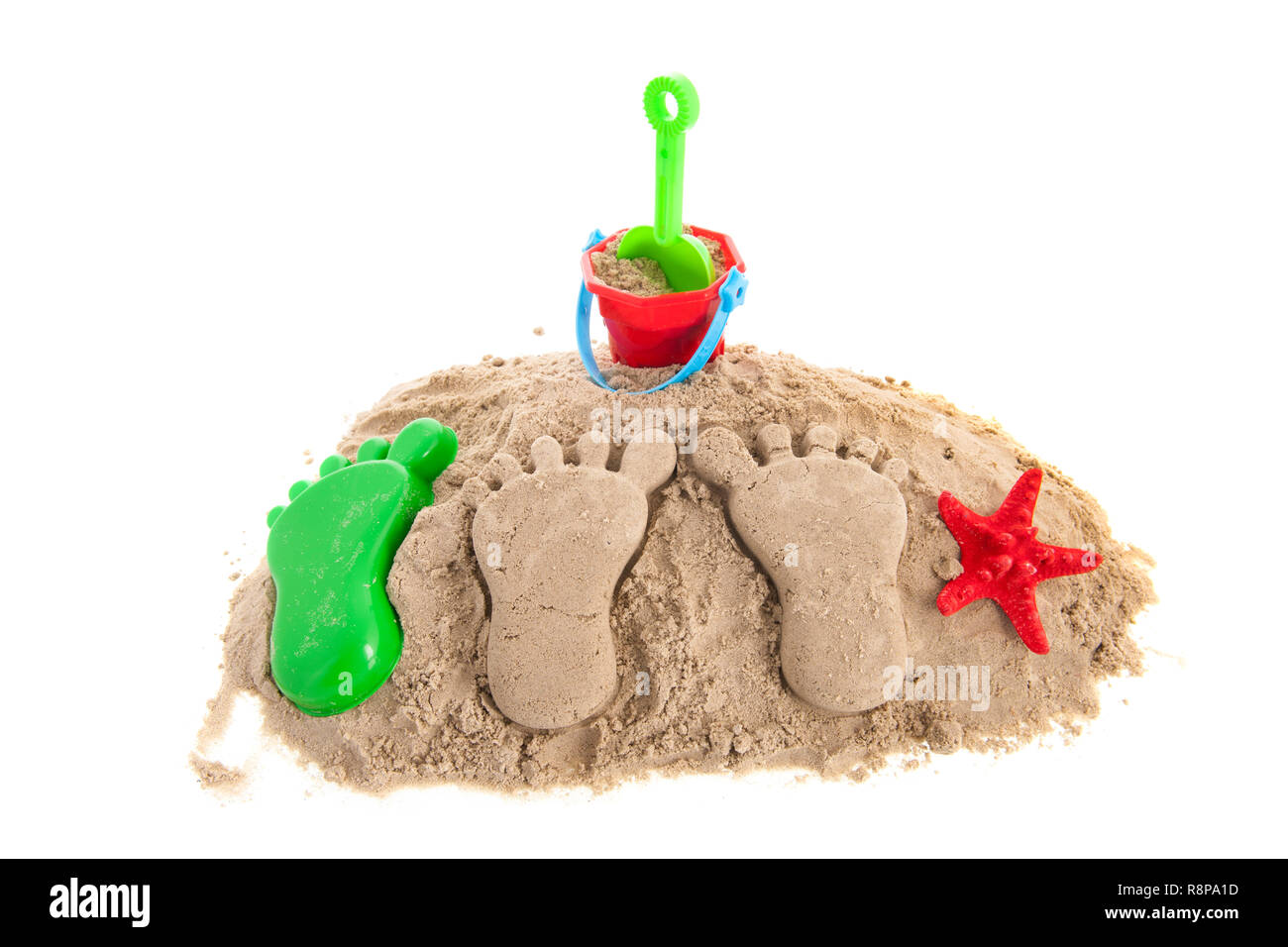 Feet prints and plastic toys at the beach isolated over white ...