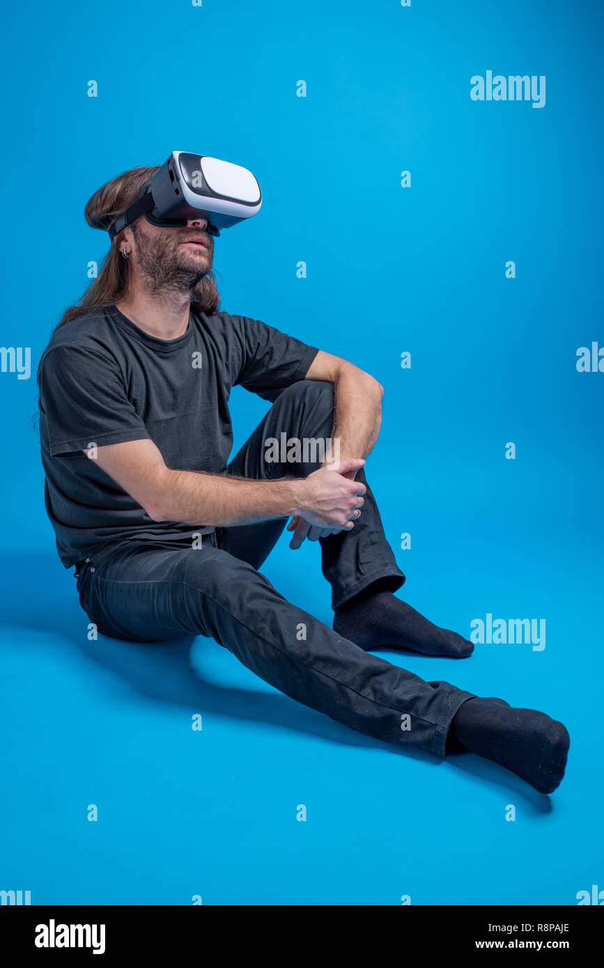 Portrait of a man standing down, looking up and enjoying a modern VR ...