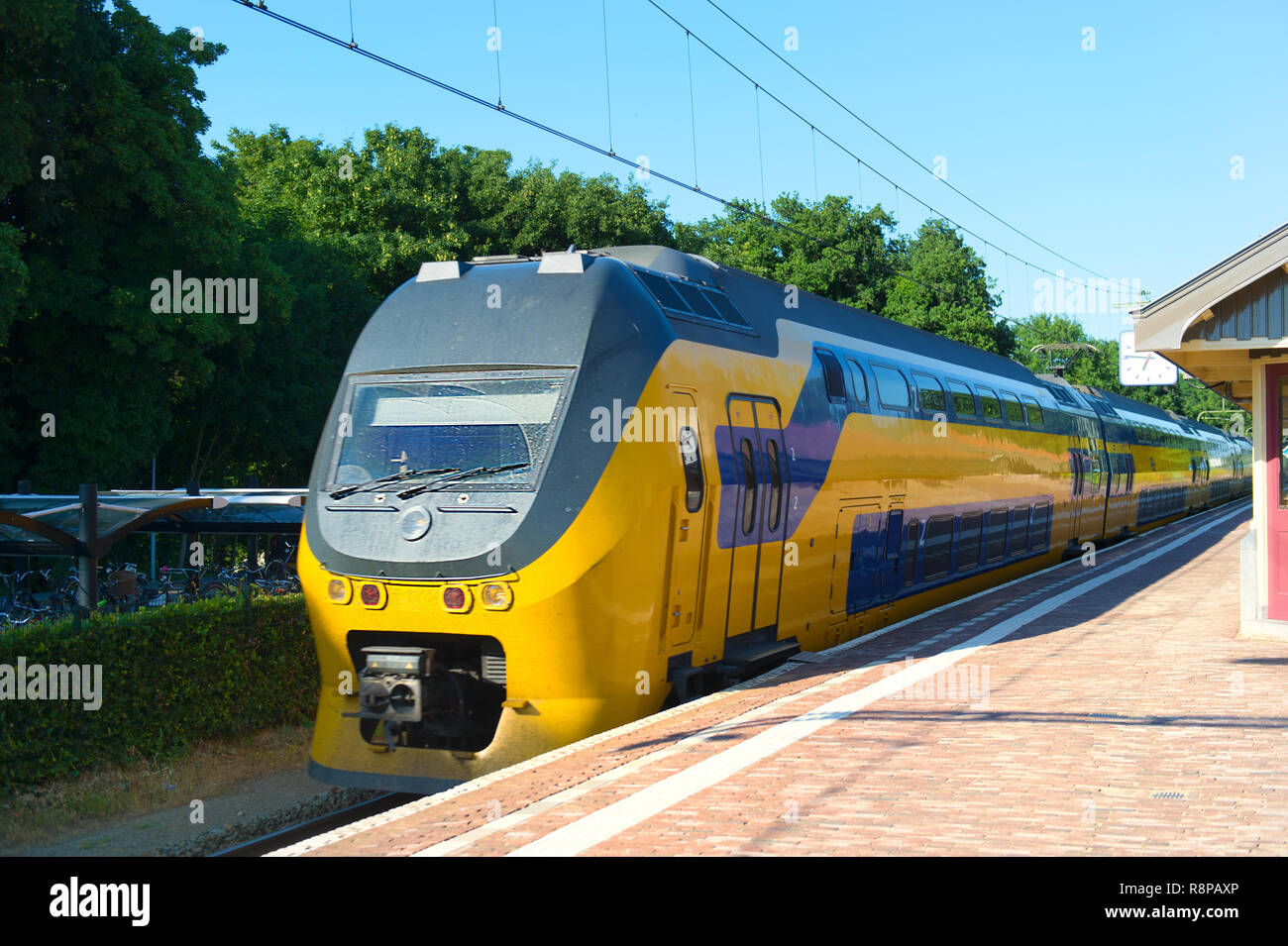Dutch railway station with yellow train in little village Den Dolder ...