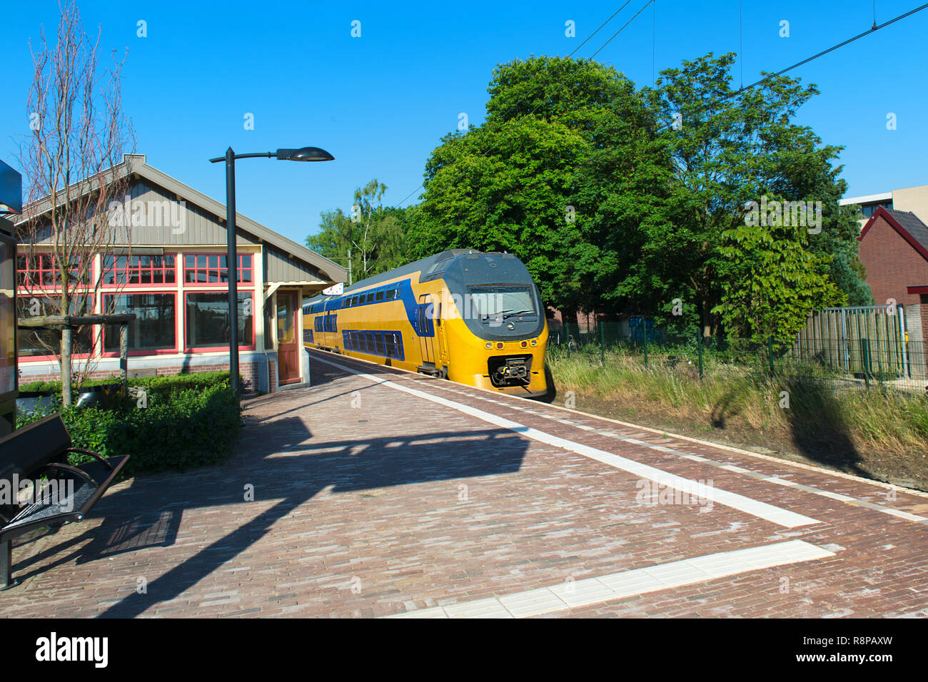 Dutch railway station with yellow train in little village Den Dolder ...