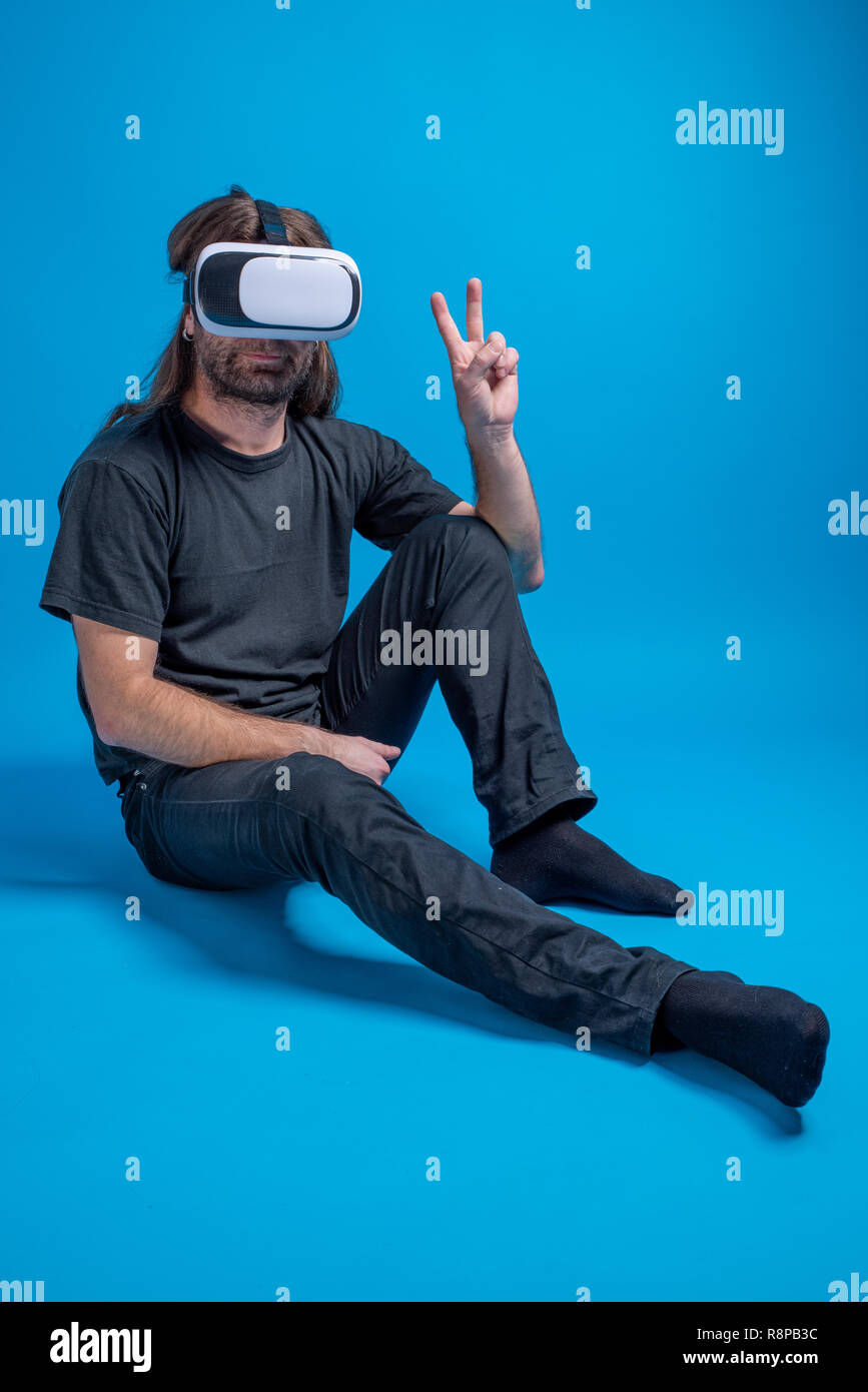 Portrait of a man standing down showing the sign of victory while using ...