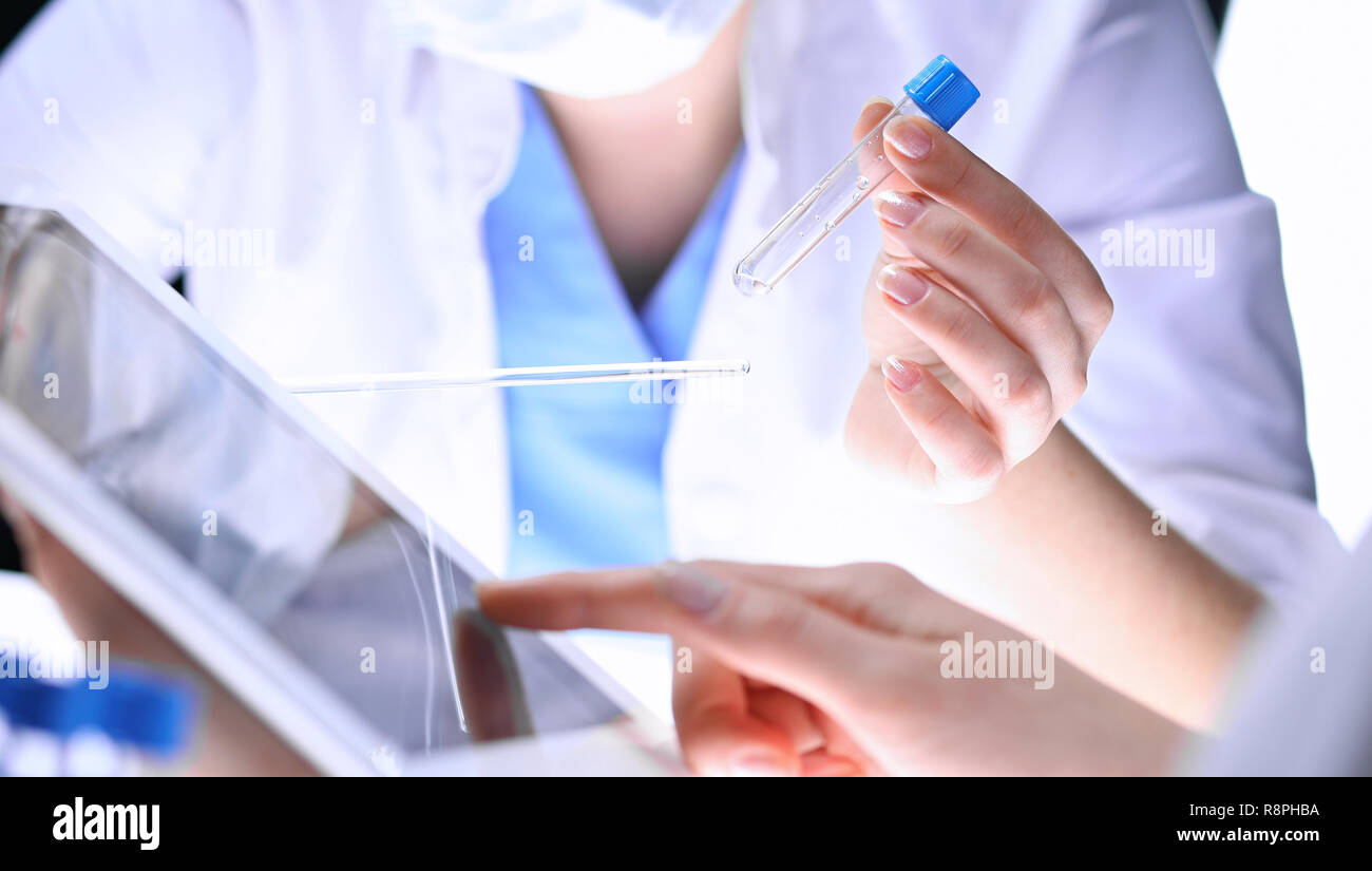 Closeup of scientific research team with clear solution in laboratory ...