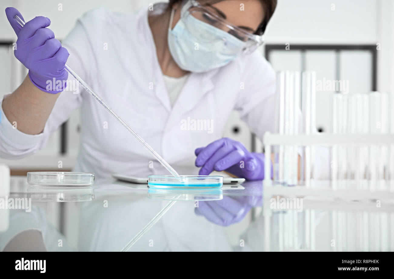 Close-up of professional female scientist in protective eyeglasses ...
