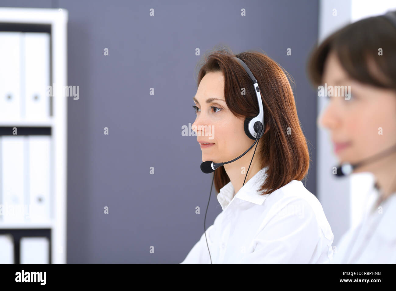 Call center. Group of operators at work. Focus on young brunette woman. Business concept Stock ...