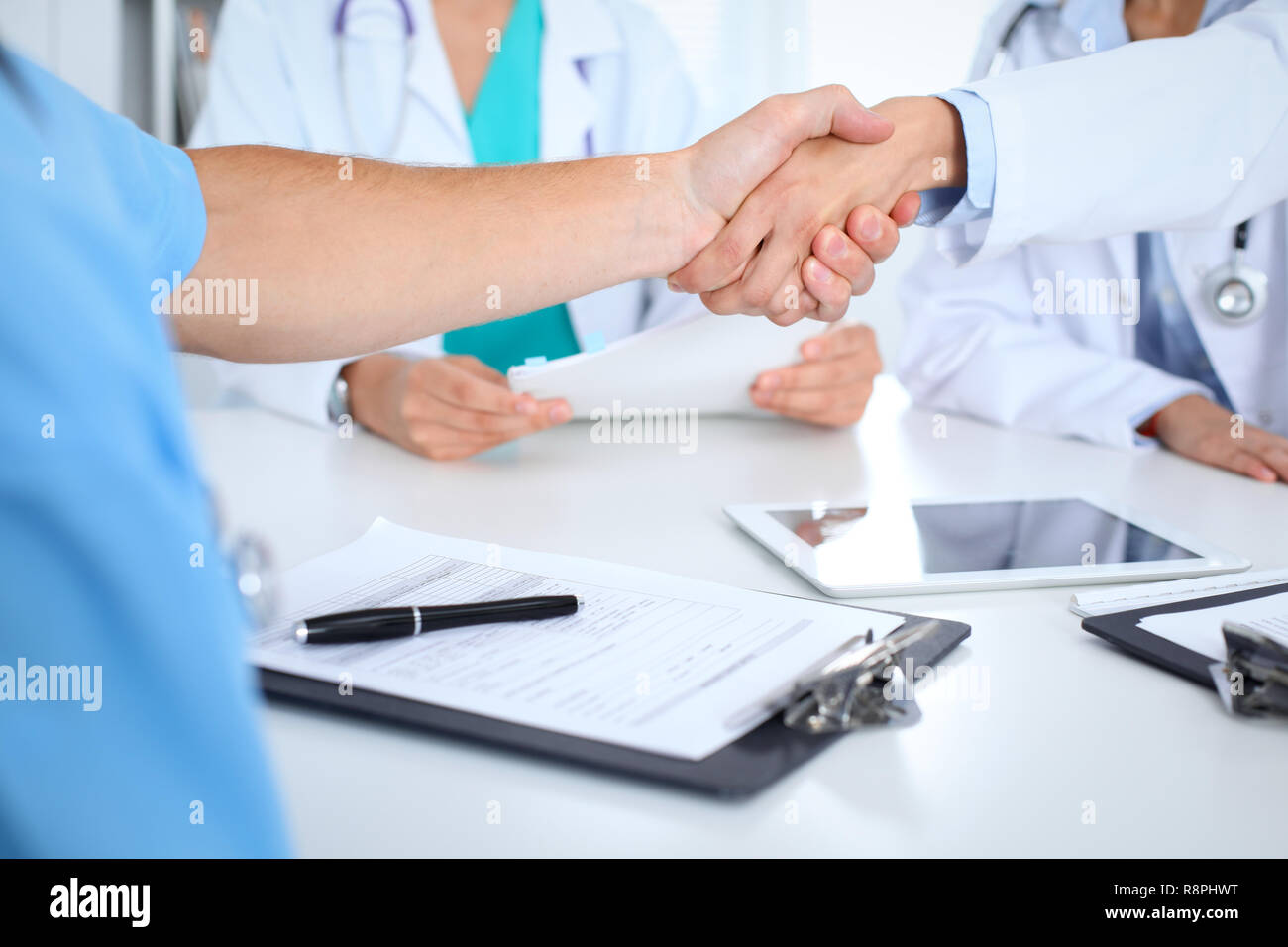 Two doctors shaking hands to each other at meeting. Teamwork and ...