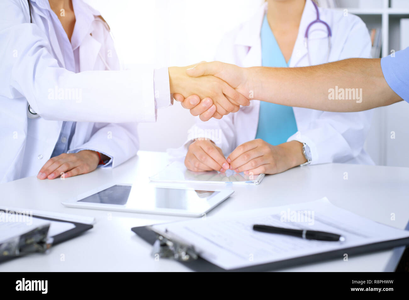 Two doctors shaking hands to each other at meeting. Teamwork and ...