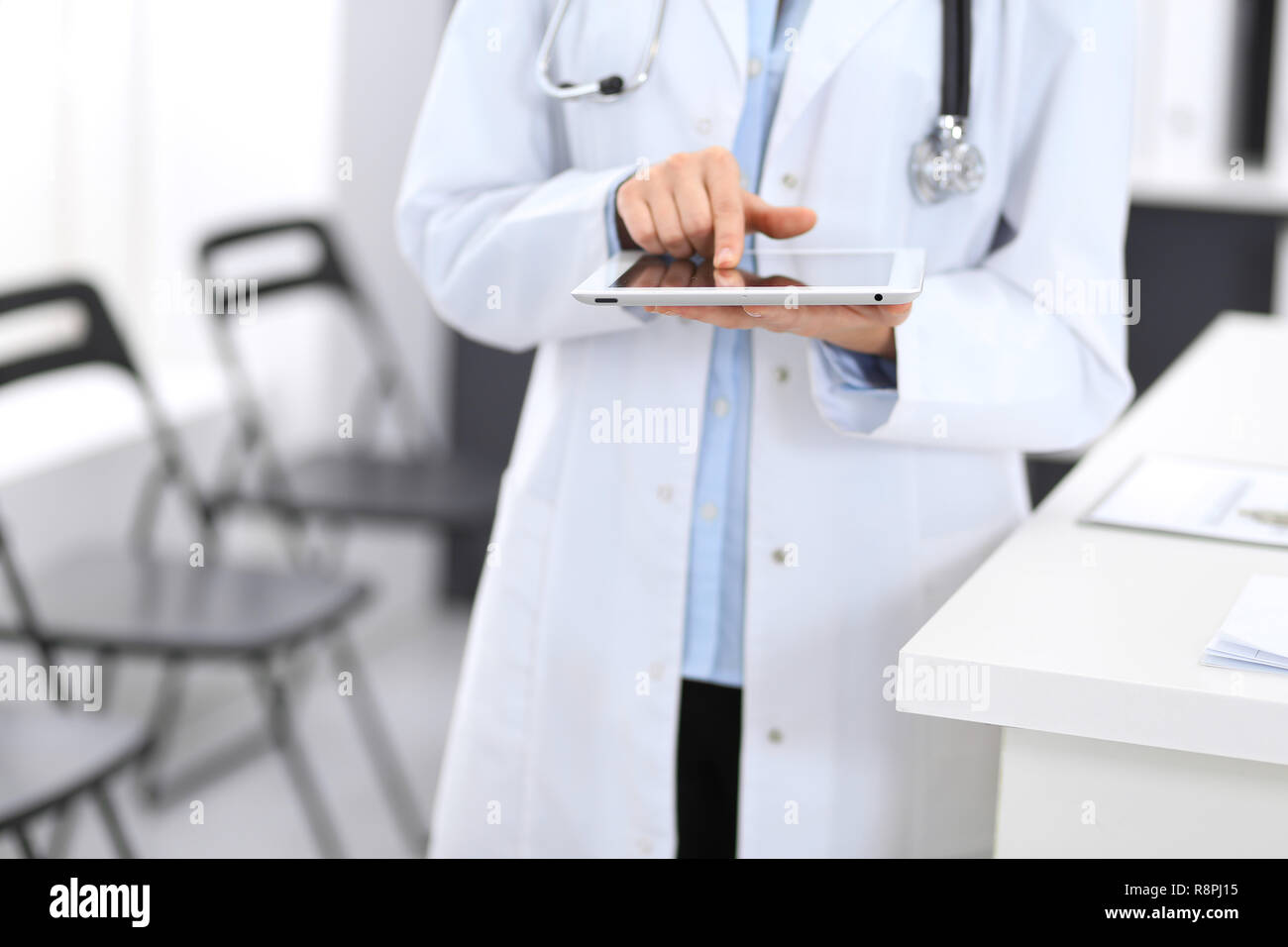 Female physician using digital tablet while standing near reception ...