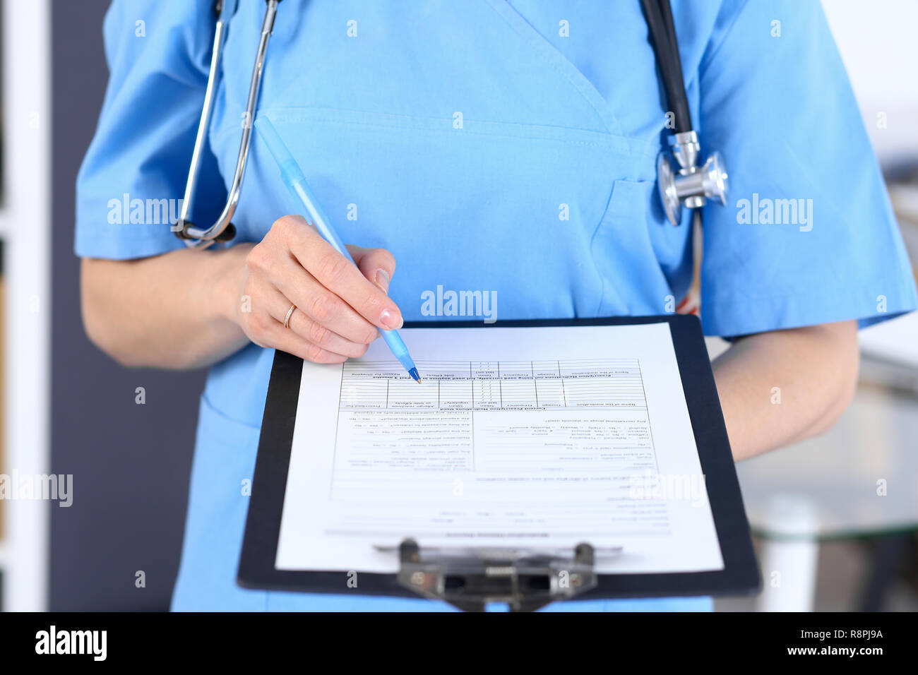 Female doctor filling up medical form on a clipboard, closeup ...
