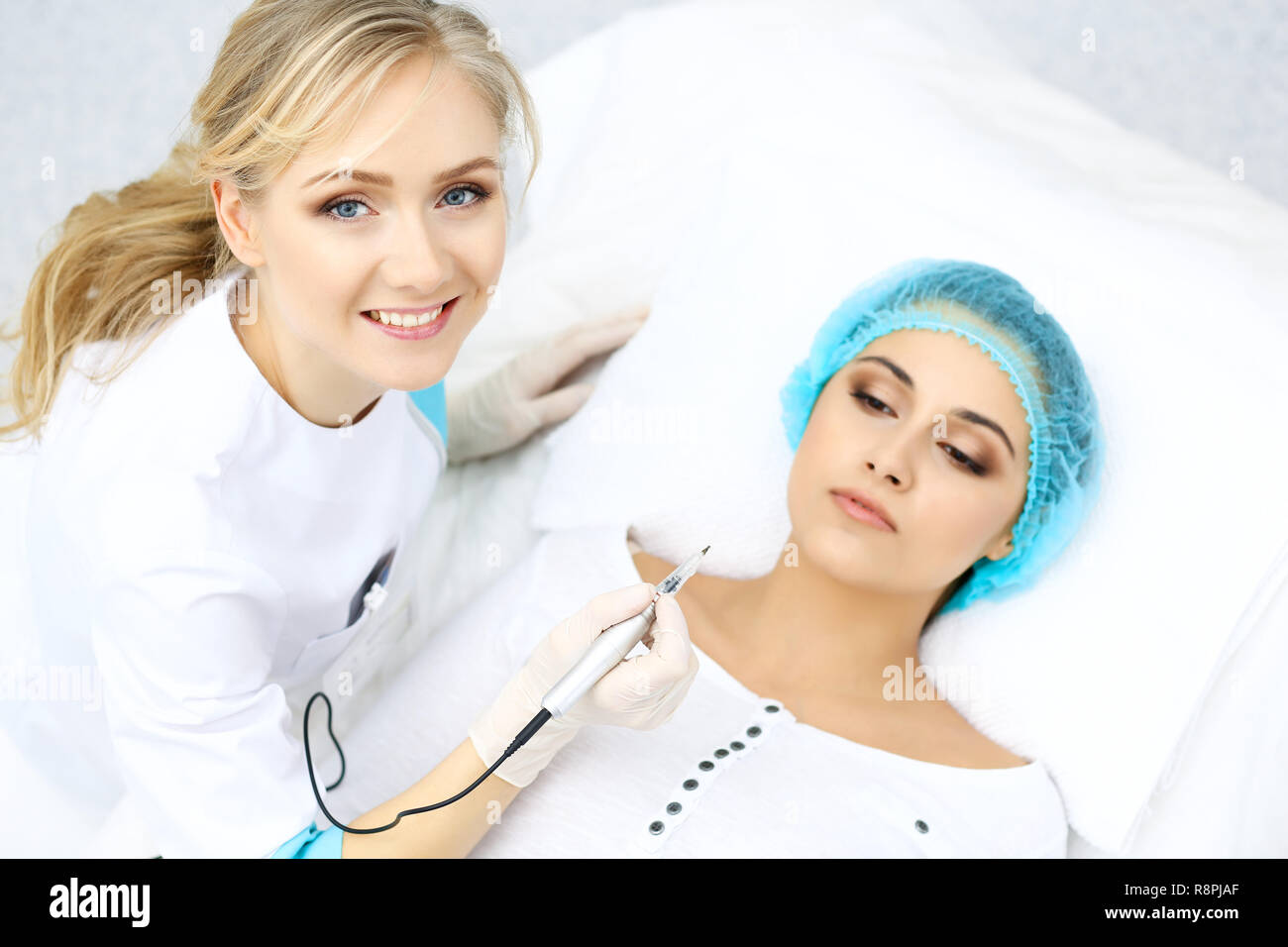 Professional beautician doing eyebrow tattoo at woman face. Permanent ...