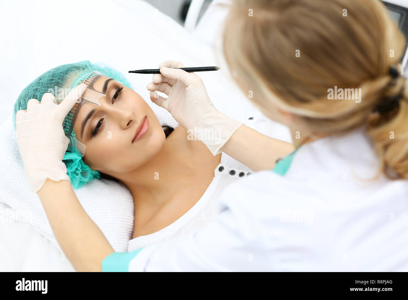 Professional beautician is going to correct eyebrow line at woman face ...