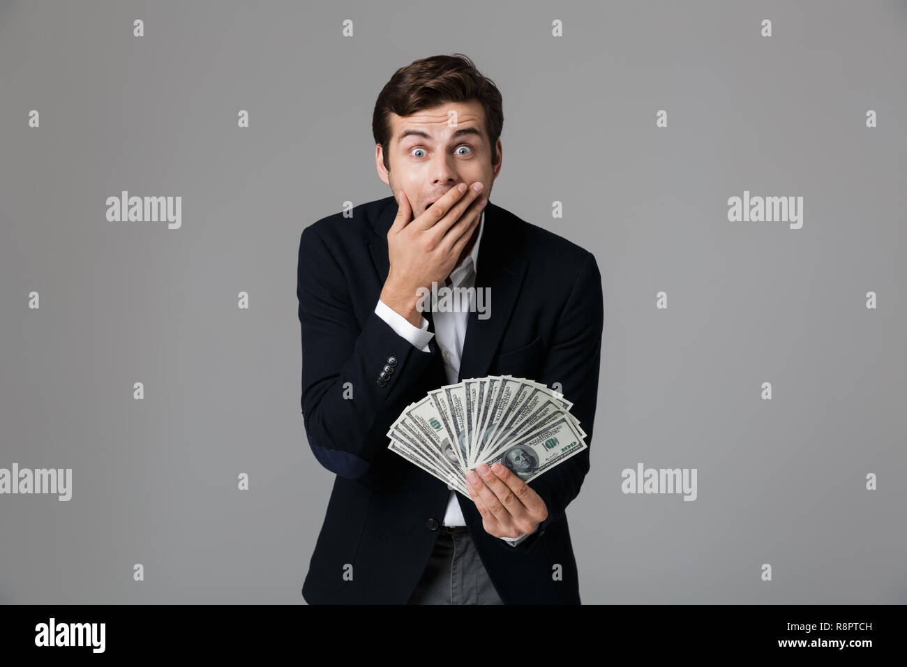 Image of surprised businessman 30s in suit smiling and holding fan of ...