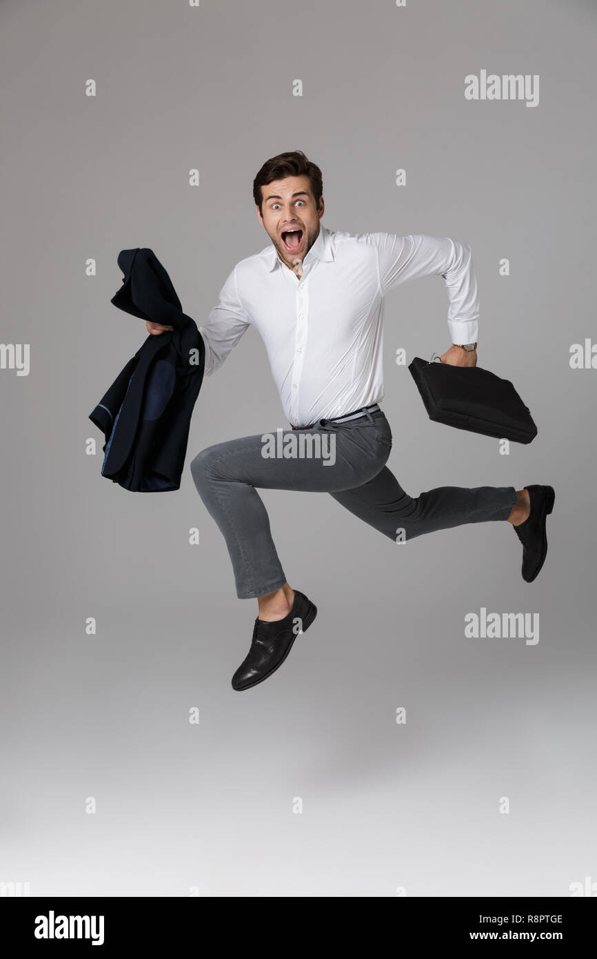 Full length image of office man 30s in business suit running with bag ...