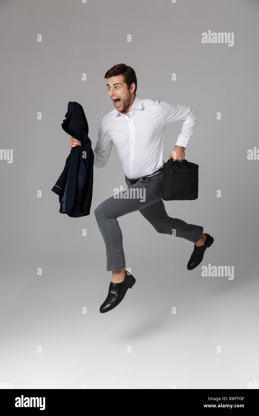 Full length image of businesslike man 30s in business suit running with ...