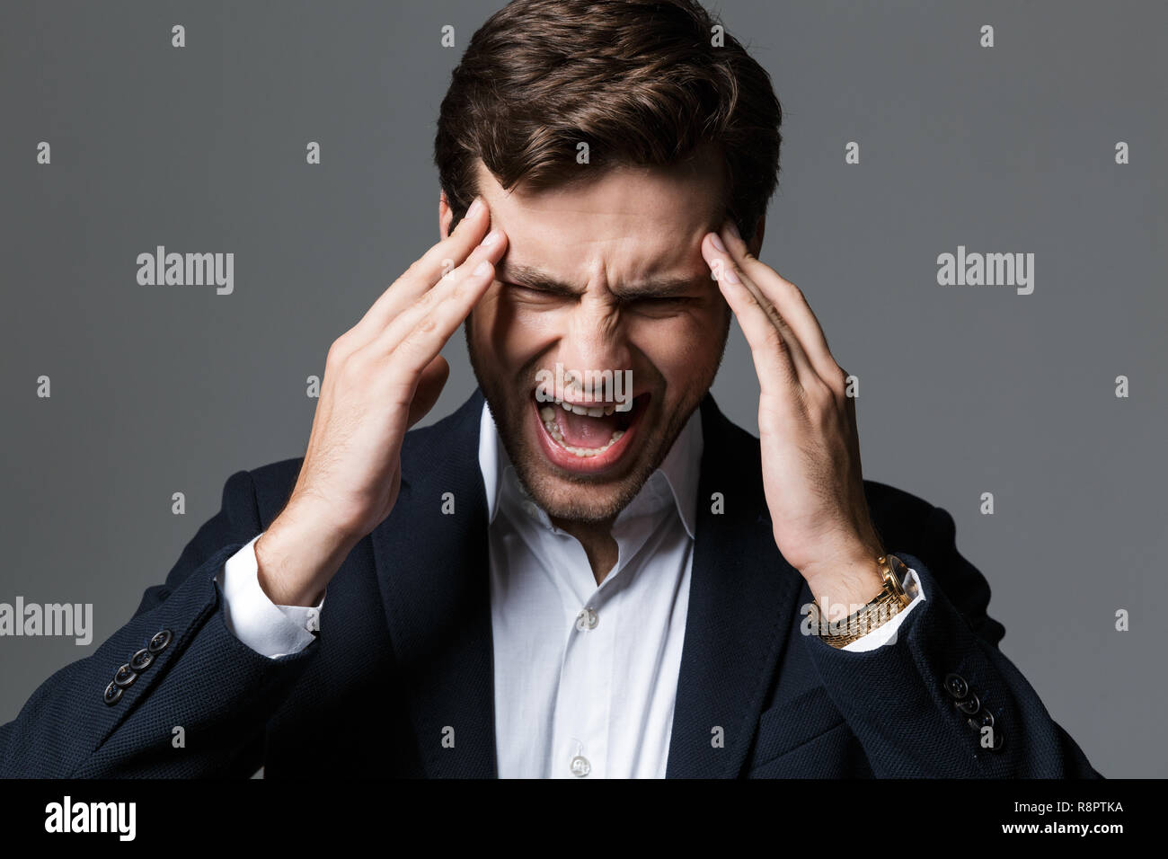 Close up portrait of a tired young businessman dressed in suit isolated ...