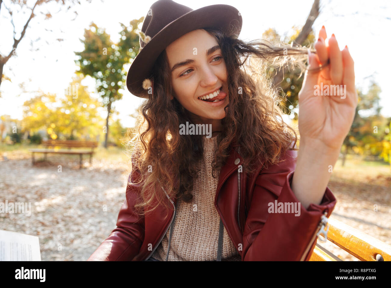 Cheerful young girl sitting on a bench at the park, reading book Stock ...