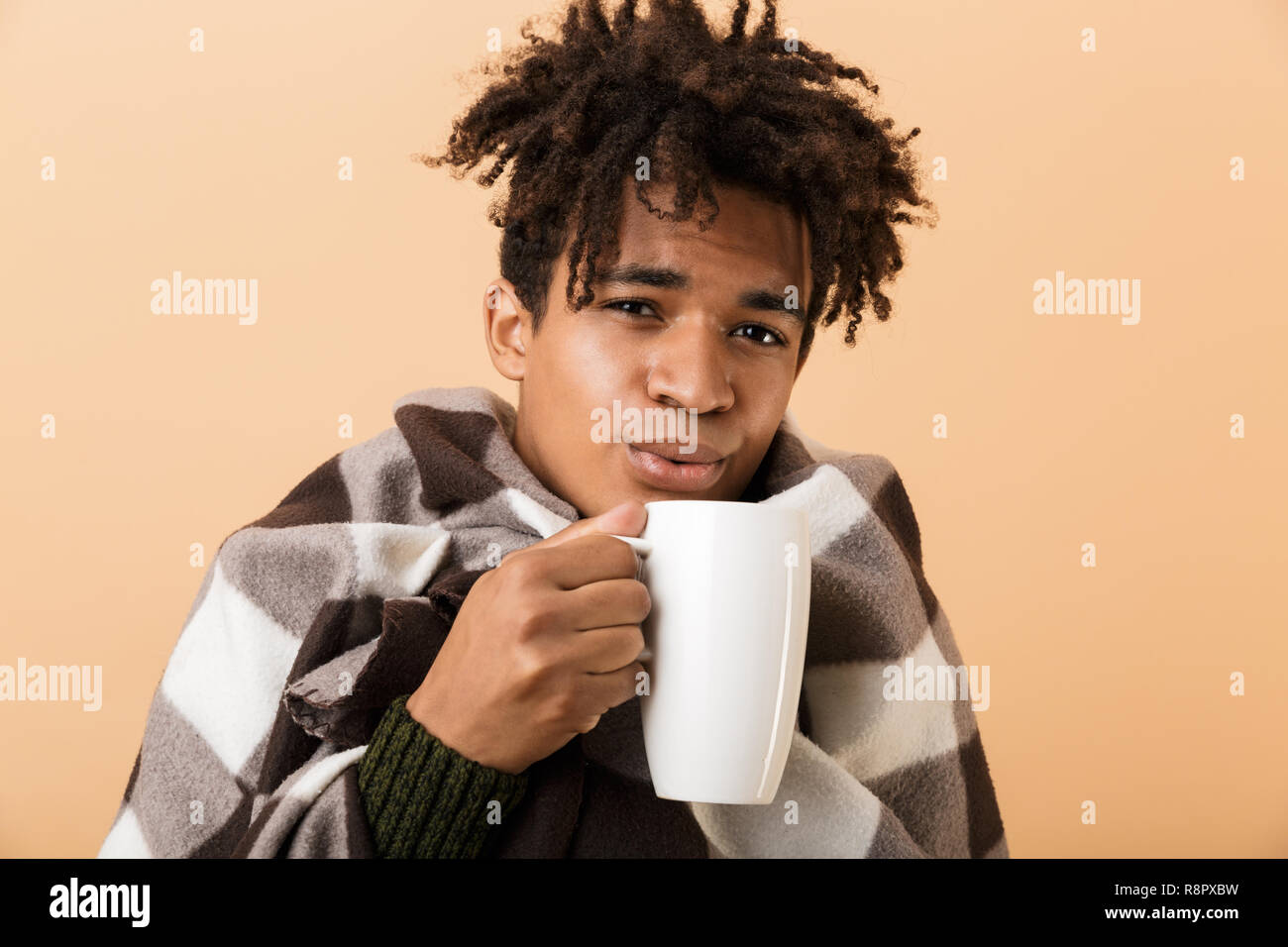 Close up portrait of a sad young african man wrapped in blanket ...