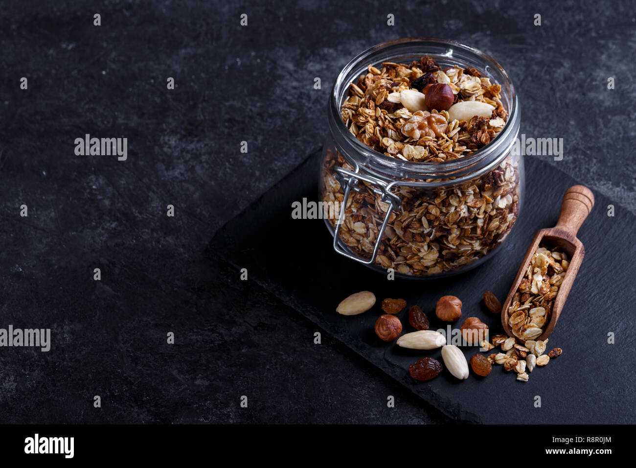 Homemade healthy granola made of oats nuts and fruits on black stone ...