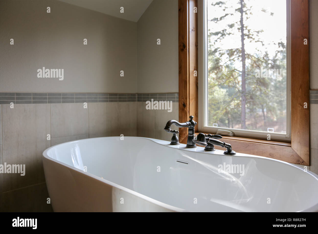 View of bathroom design with a white sleek freestanding tub under a ...