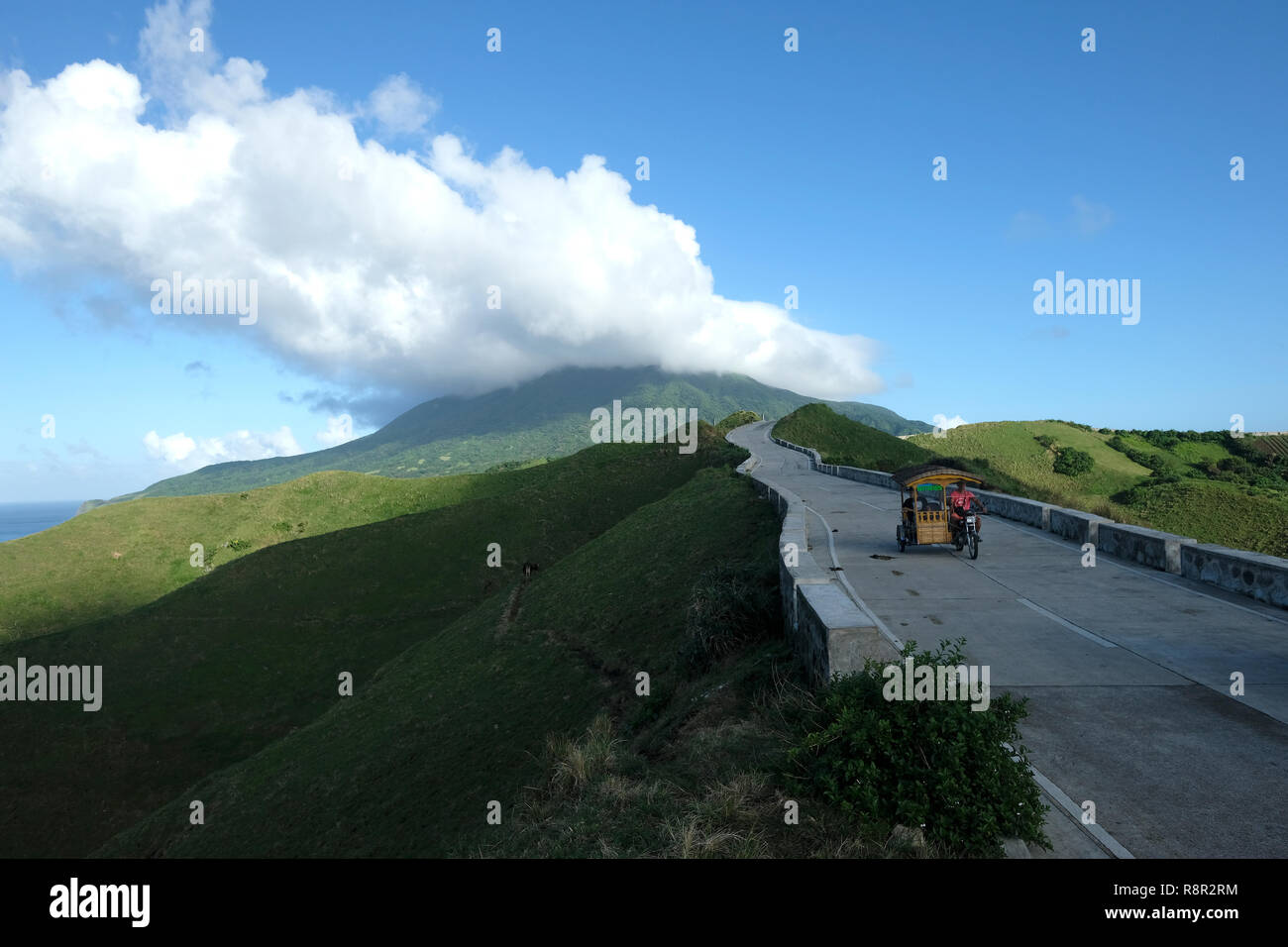 A man rides a tricycle motorcycle taxi through at Vayang Rolling Hills ...