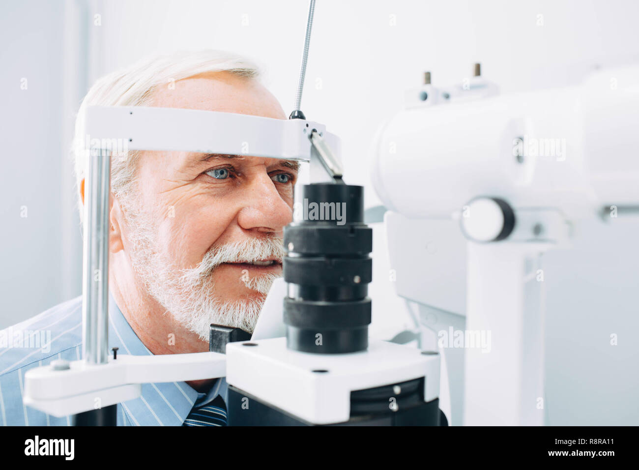 Senior man receiving eye exam at clinic, eyesight examination aged ...