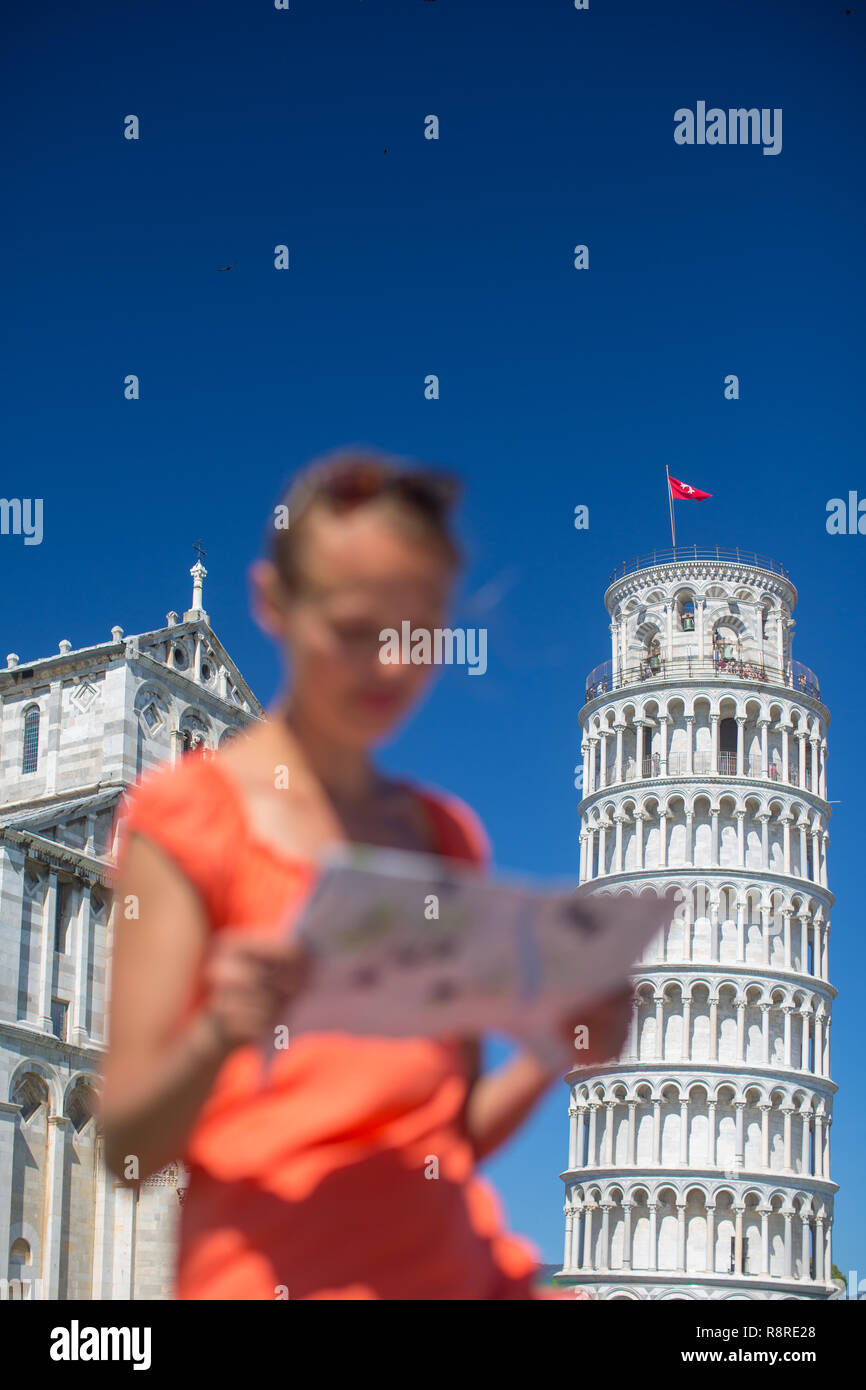 Gorgeous female tourist with map admiring the Leaning Tower of Pisa ...