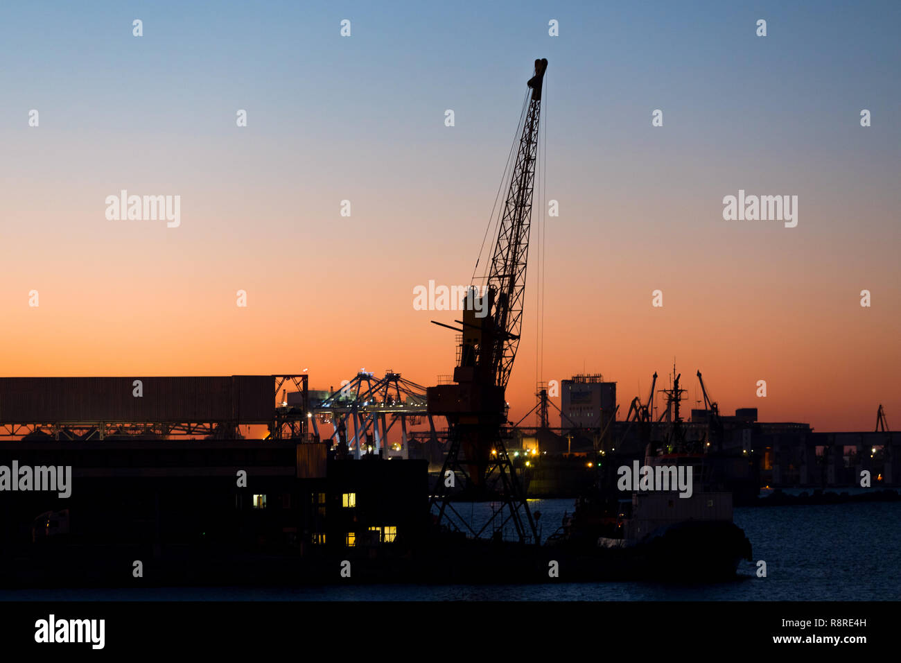 Cargo port cranes on a background of sunset sky Stock Photo - Alamy