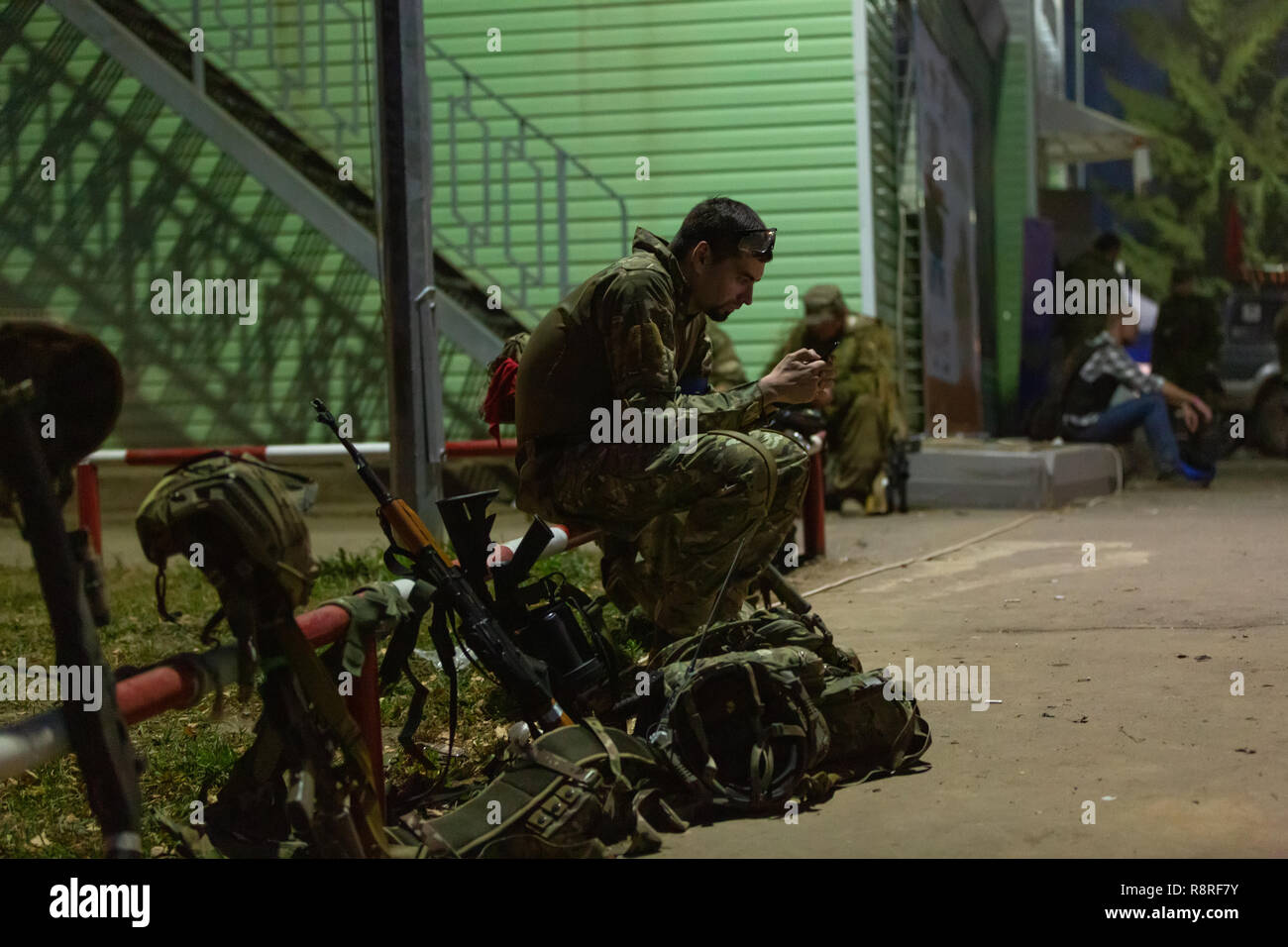 Side view serious soldier writing message in phone while wearing in ...