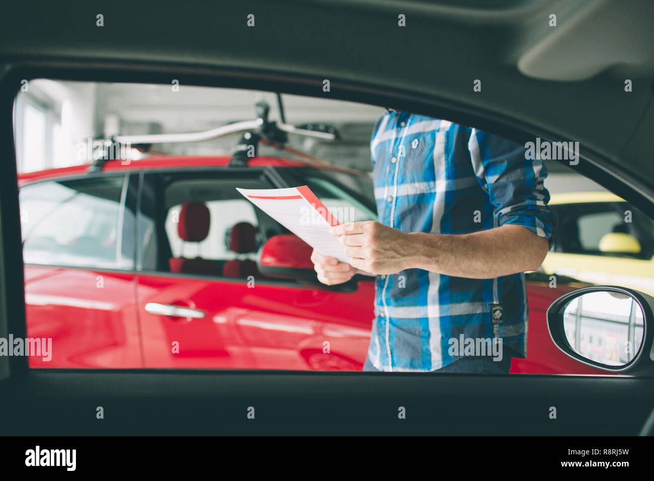 Perfect lines. The young dark-haired bearded man examining car at the ...