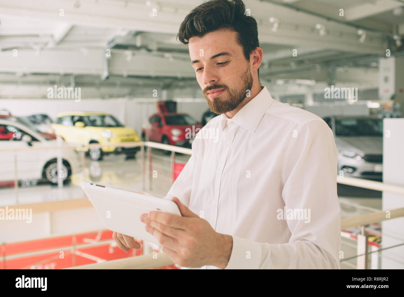 friendly vehicle salesman presenting new cars at showroom. Photo of ...