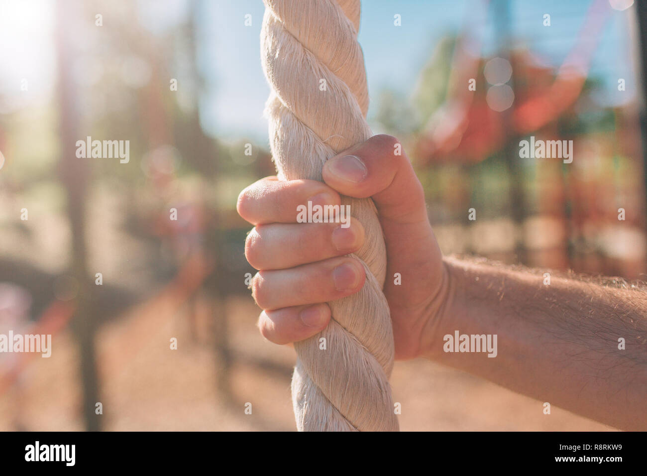 closeup of Man's hairy arms grasping or holding a rope indicating ...