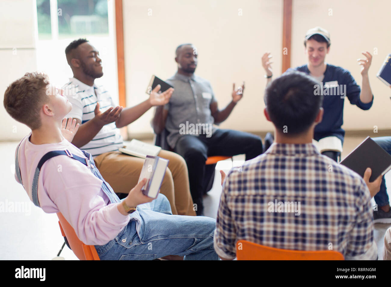 Men with bibles praying with arms outstretched in prayer group Stock ...