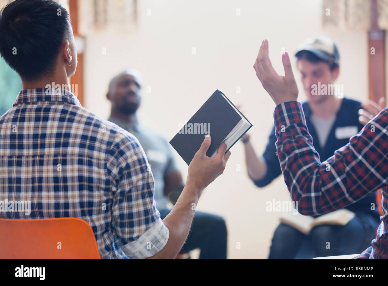 Men with bible praying with arms raised in prayer group Stock Photo - Alamy