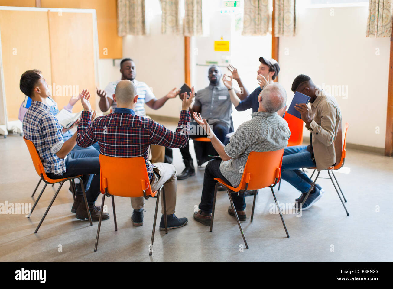 Men praying with arms raised in circle in prayer group Stock Photo - Alamy