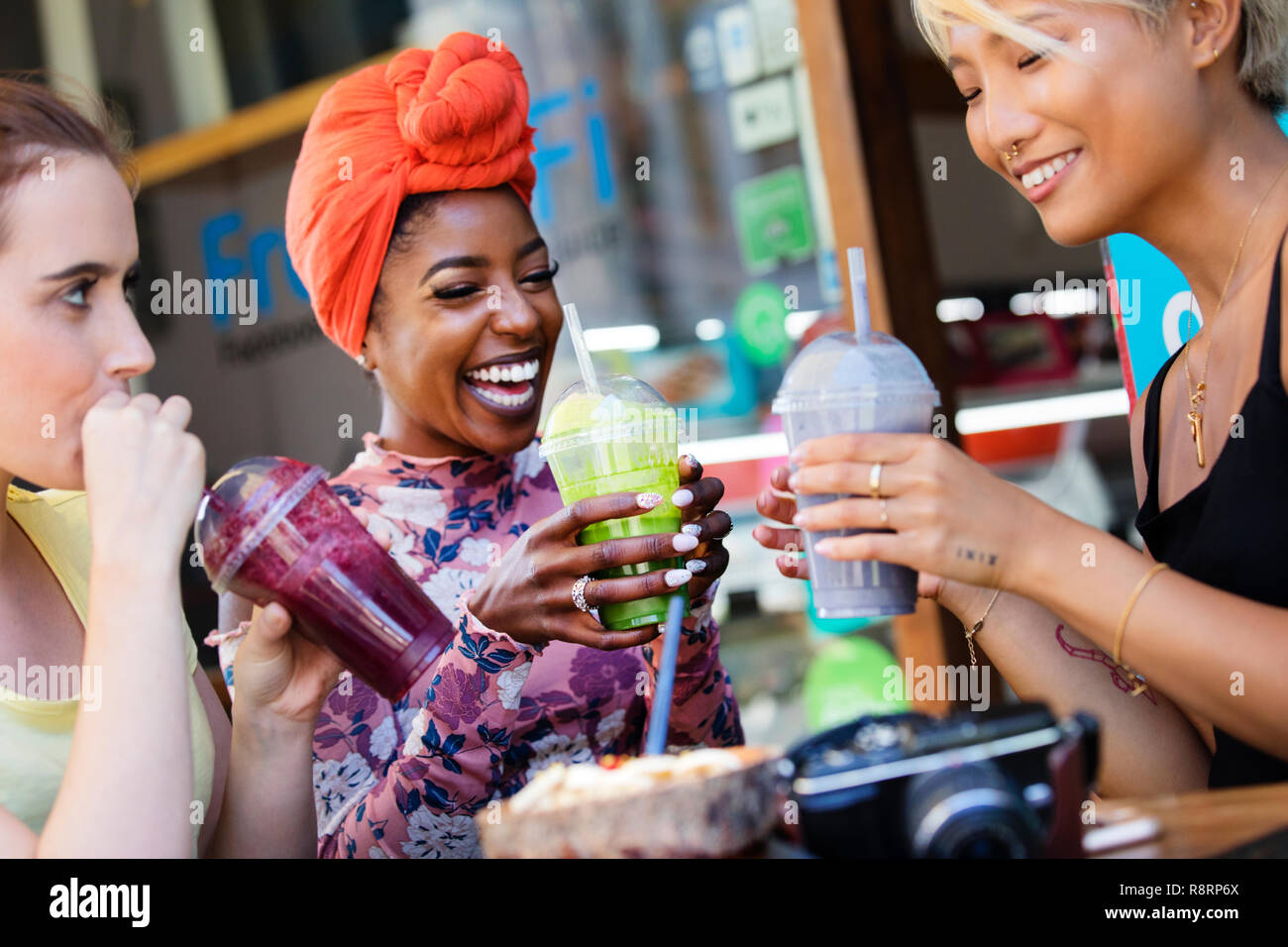 Young women friends drinking smoothies at sidewalk cafe Stock Photo - Alamy