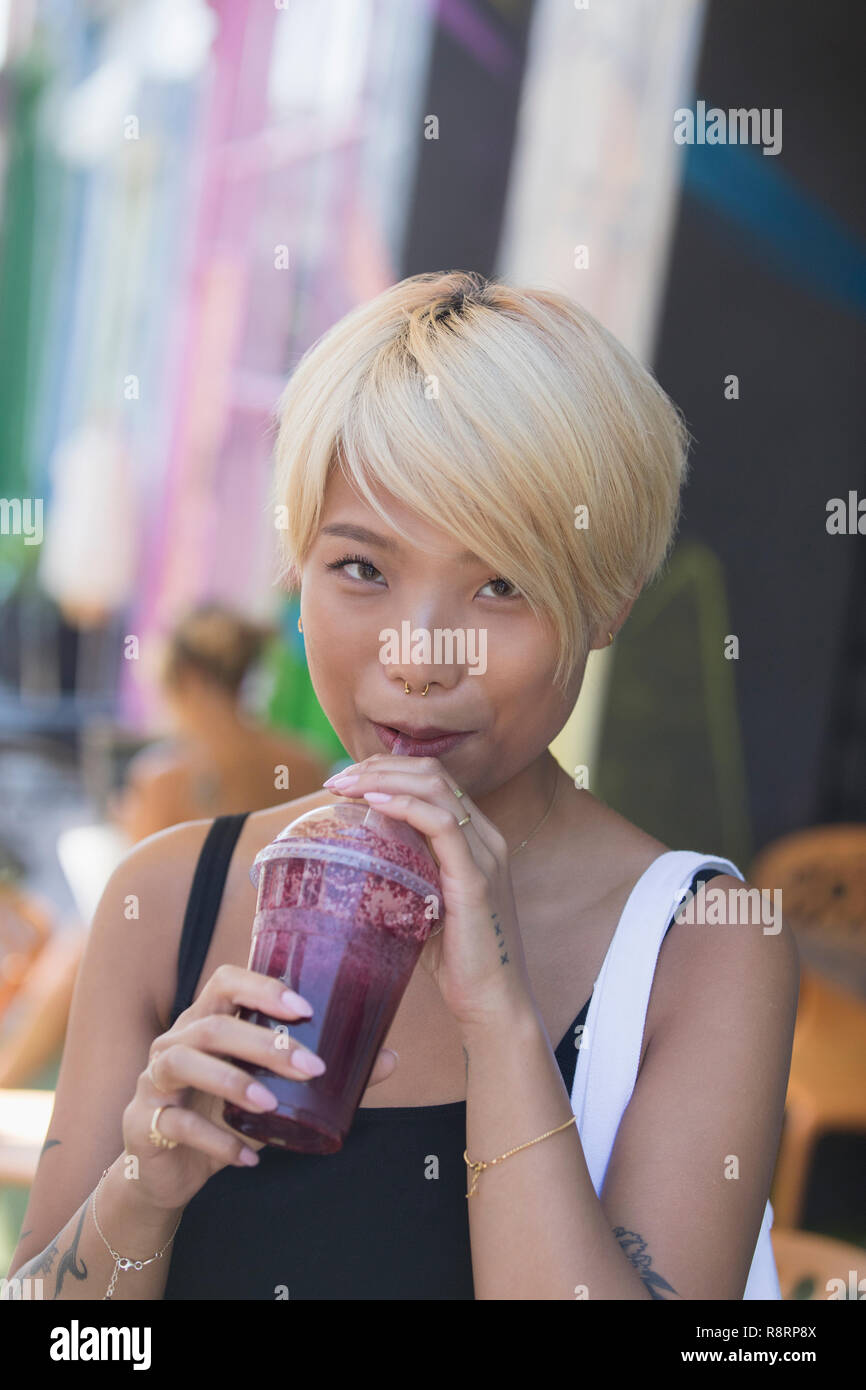 Portrait smiling young woman drinking smoothie Stock Photo - Alamy