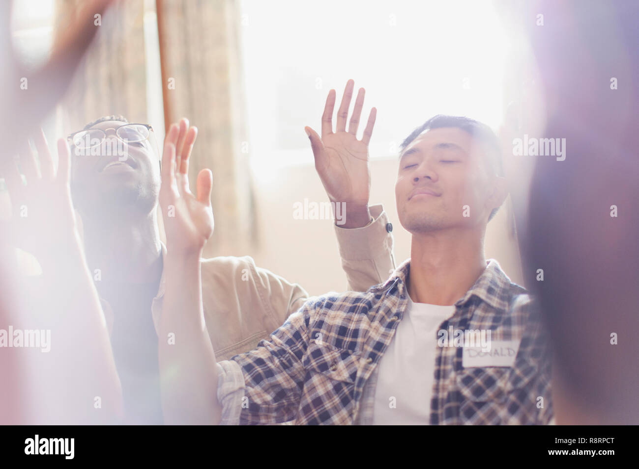 Serene men praying with arms raised in prayer group Stock Photo - Alamy