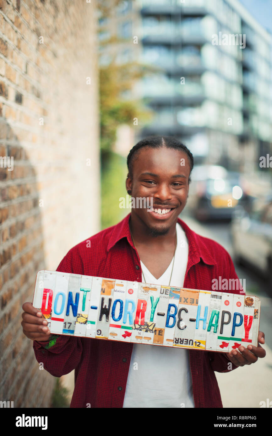 Portrait smiling teenage boy holding Dont Worry Be Happy license plates ...