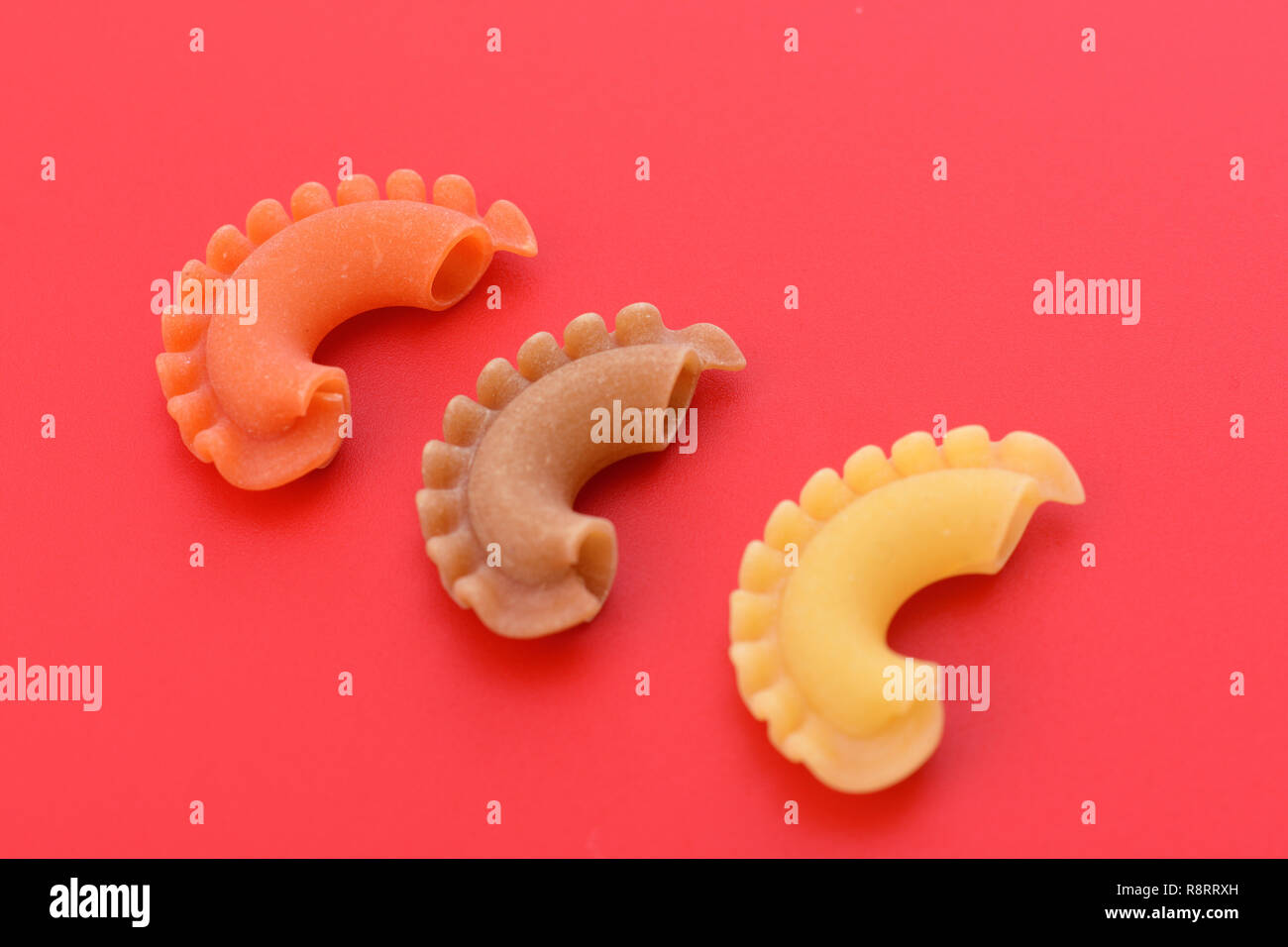 Pasta creste di gallo on red background Stock Photo - Alamy