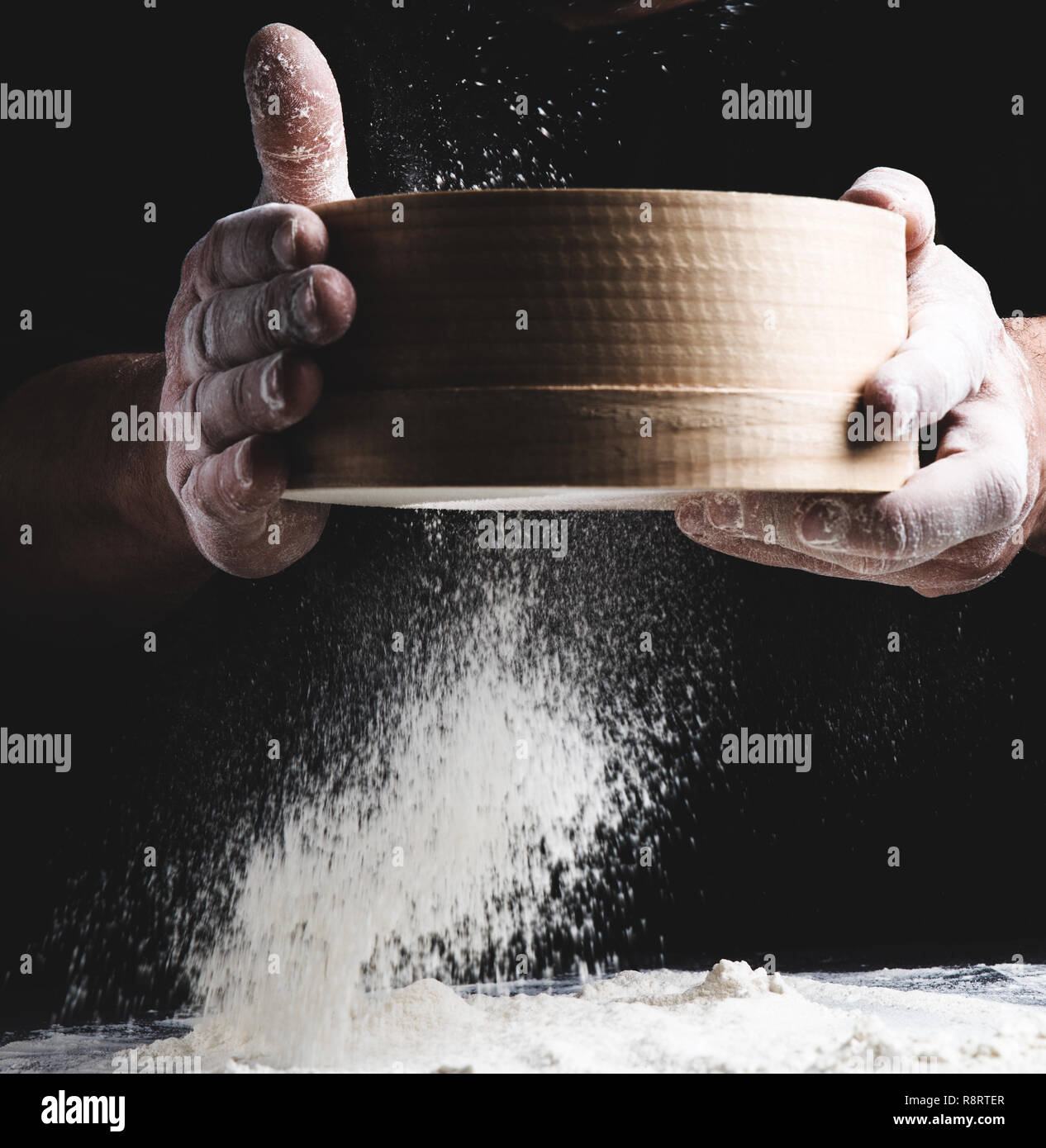 round wooden sieve with flour in male hands, the chef sifts white wheat ...