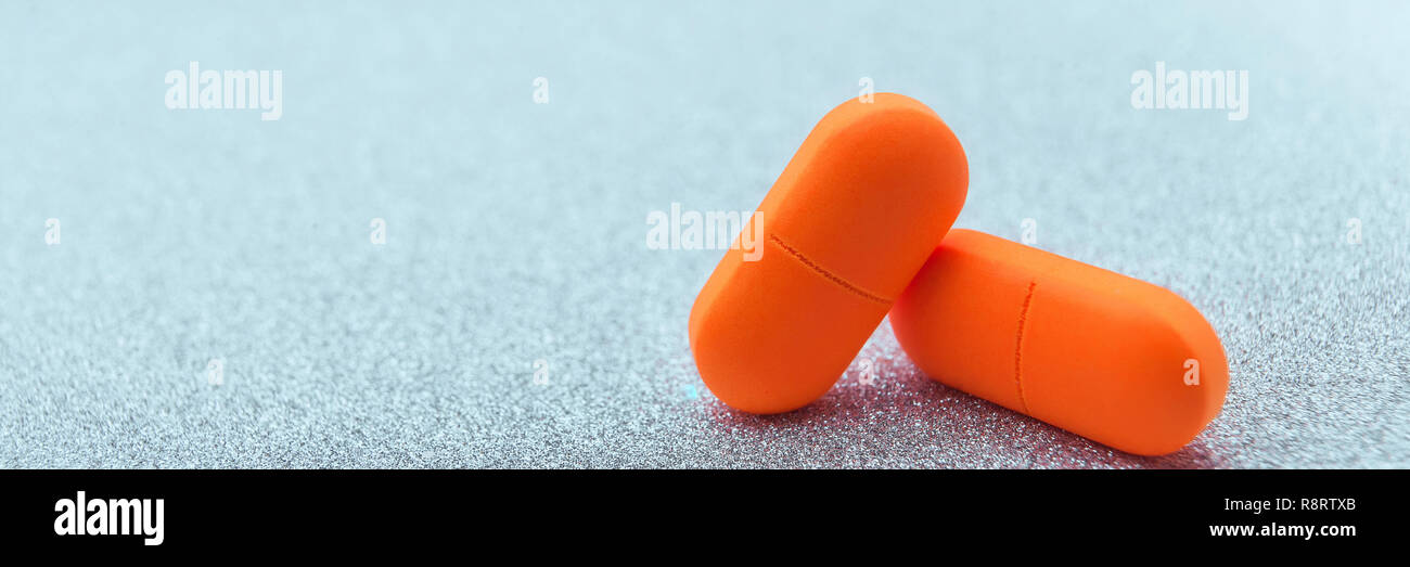 two red pills close up on blue glitter, sparkles, sparkling background ...