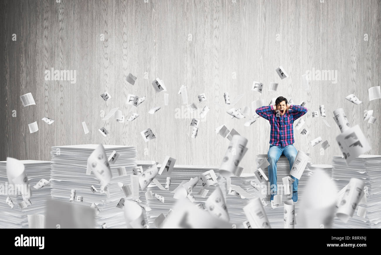 Attractive man sitting on pile of paper documents Stock Photo - Alamy