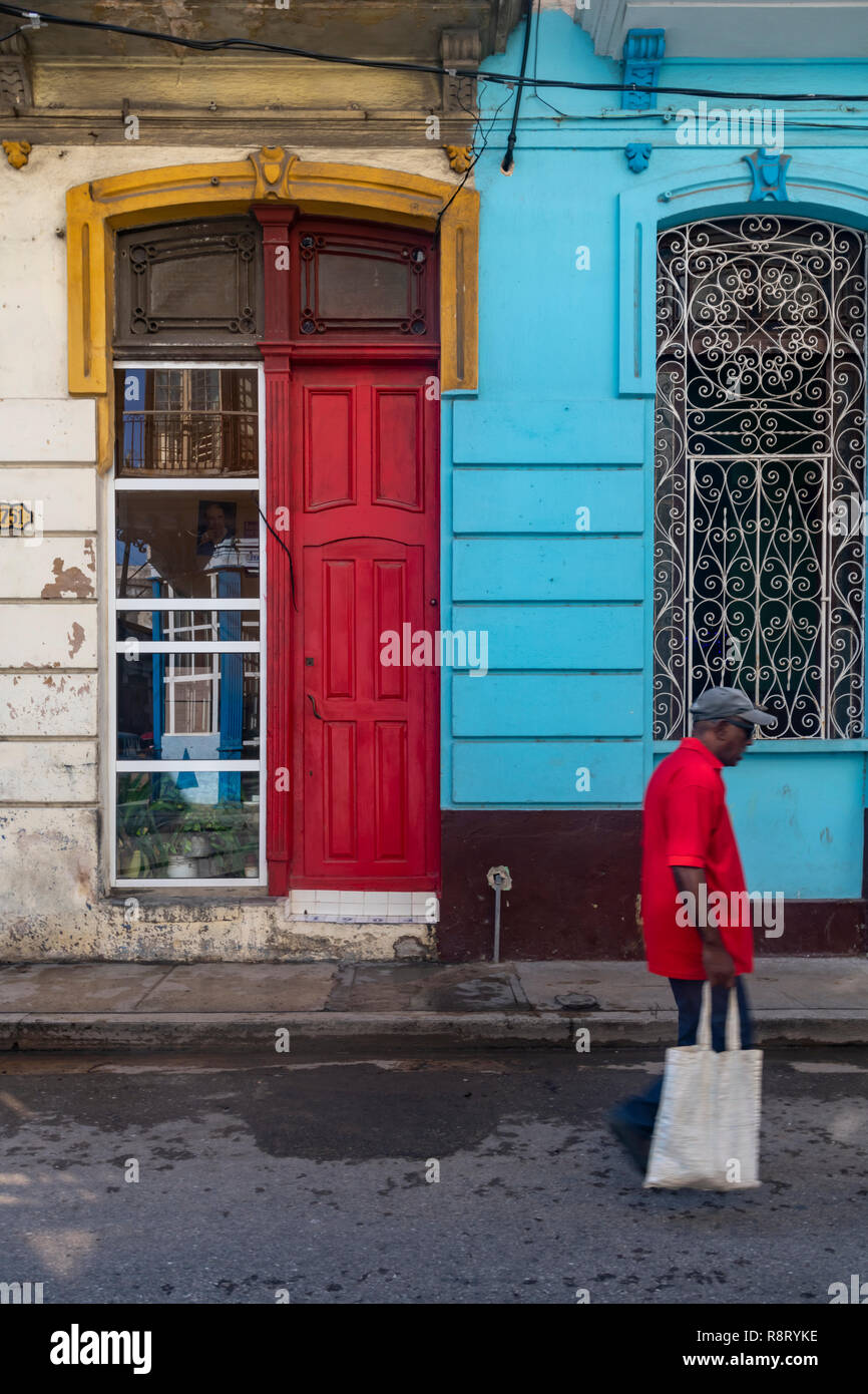 Cuban Man with carrier bag walking along brightly coloured street in ...