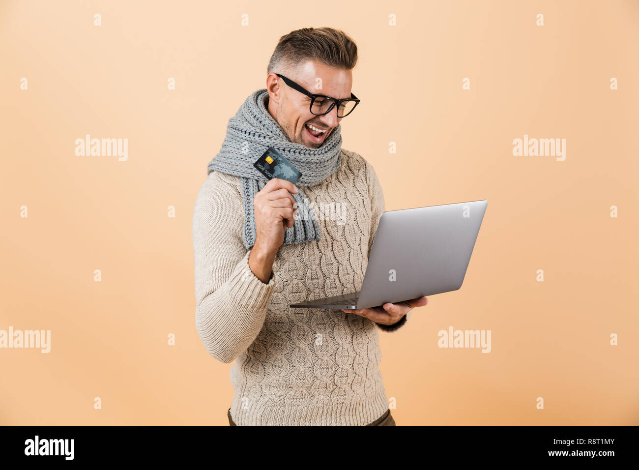 Portrait if a happy man dressed in sweater and scarf standing isolated ...